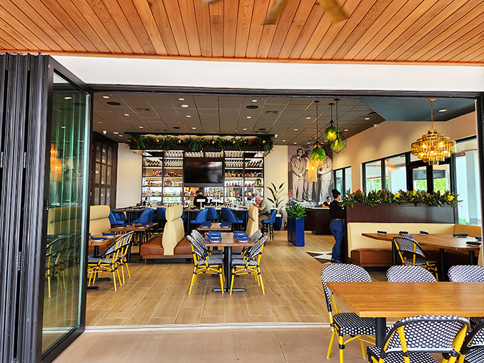 Floor-to-ceiling windows flood the space with natural light, while plants add touches of green to the sophisticated wood and blue palette.