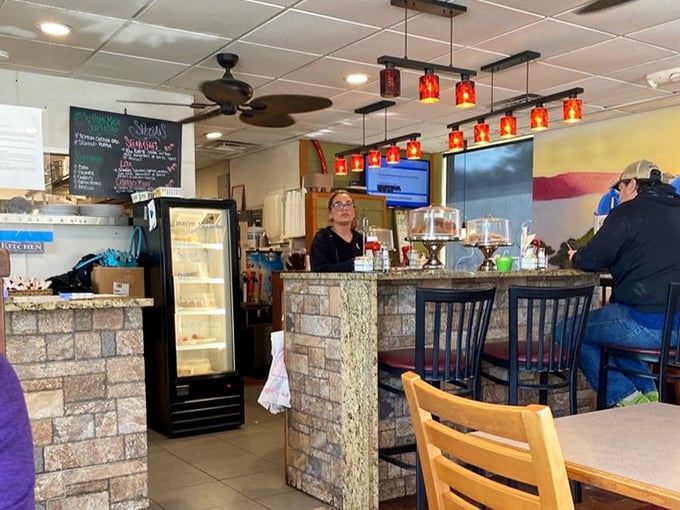 Behind the counter, where breakfast magic happens. The chalkboard specials and red pendant lights add to the classic neighborhood cafe charm.