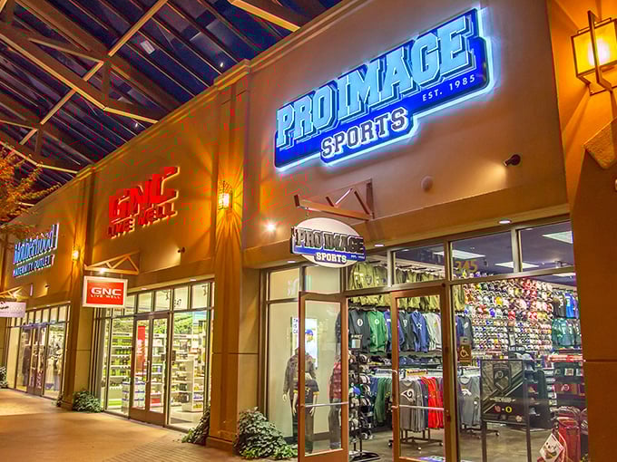 Evening shopping takes on a magical quality as store lights illuminate the walkways with a warm, inviting glow. 
