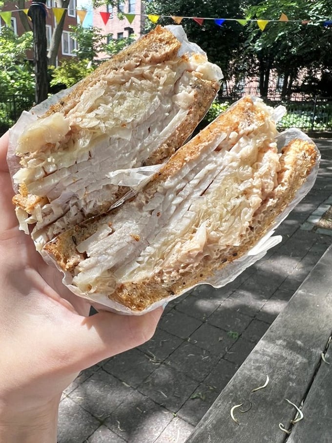 Behold the turkey sandwich in its natural habitat—layers of thinly sliced meat and sauerkraut creating a portable masterpiece worth traveling for.