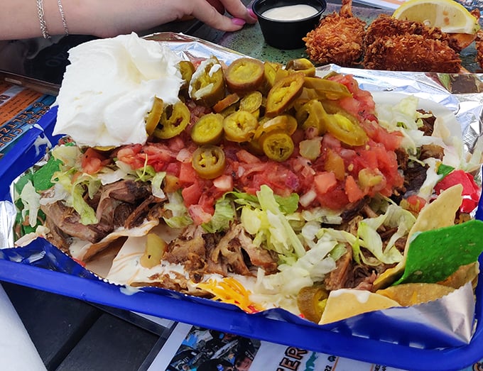 Nachos that require a strategy meeting before eating—where every chip is a delivery vehicle for pulled pork, jalapeños, and enough cheese to make Wisconsin proud.