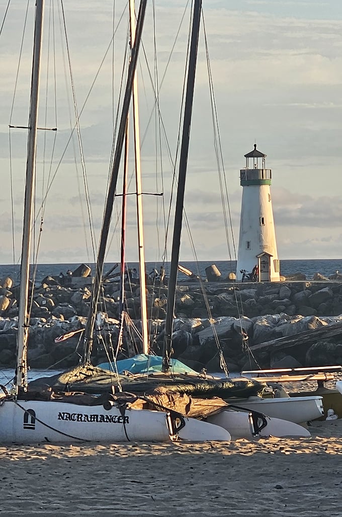 The perfect framing: sailboat masts in the foreground create leading lines that draw your eye directly to the lighthouse's pristine silhouette.