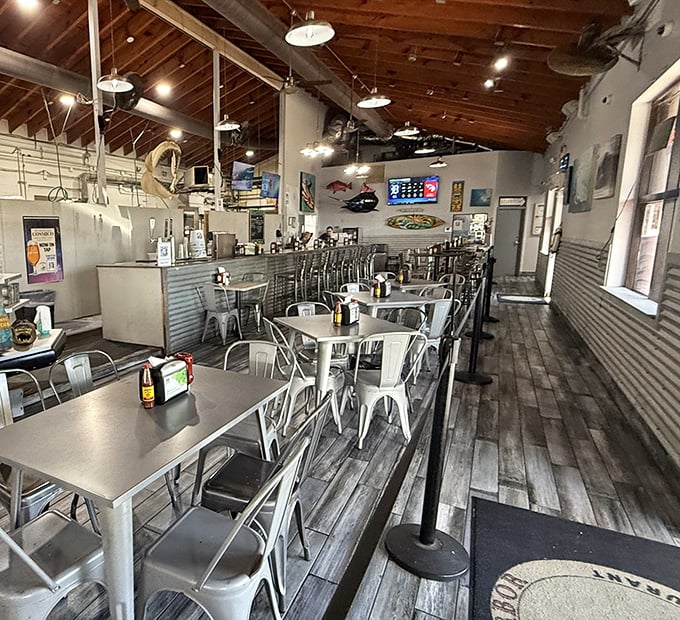 Industrial-chic meets fishing village aesthetic – metal chairs, wooden floors, and nautical touches create the perfect seafood backdrop.