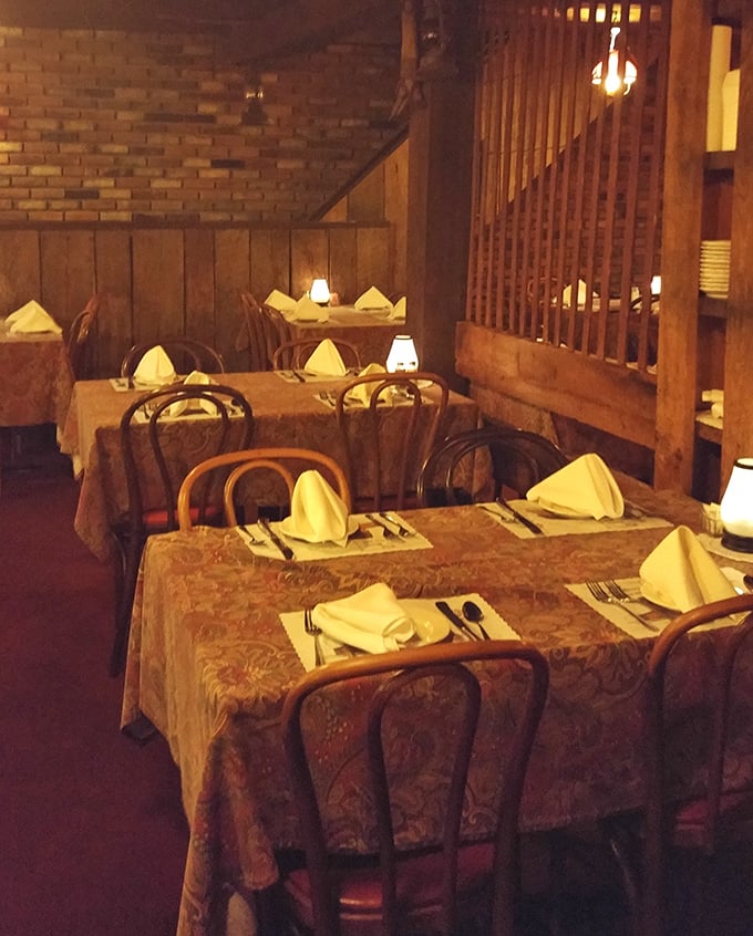 White tablecloths and carefully folded napkins signal that this rustic setting takes its food seriously – country charm meets culinary precision.