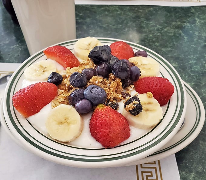 A breakfast masterpiece of yogurt, granola, and fresh fruit – the kind of healthy choice that makes you feel virtuous enough to order dessert later.