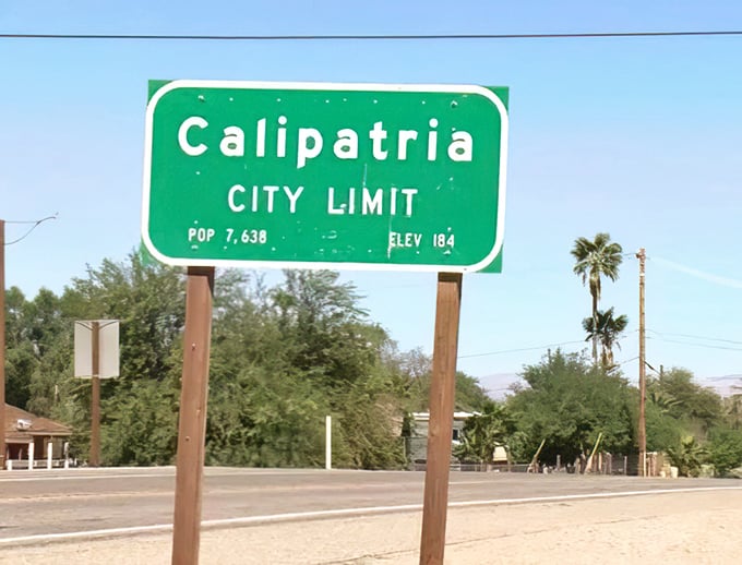 The city limit sign tells a story in numbers: population 7,638, elevation -184 feet—a community literally living below sea level but certainly not beneath notice.