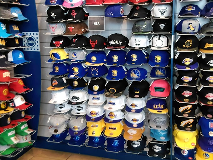 A wall of sports caps displays team loyalties like a colorful census of California's divided sports allegiances—choose your tribe carefully.