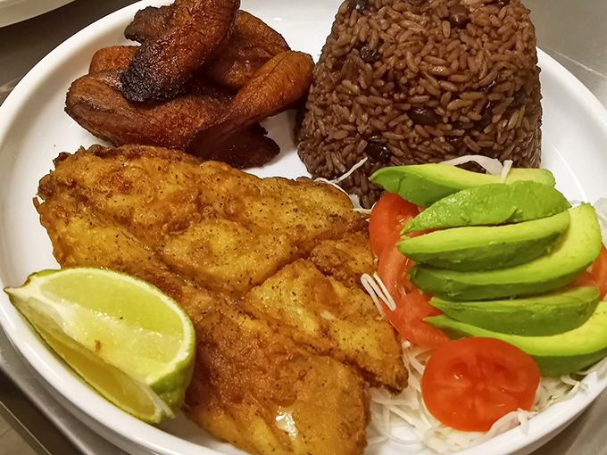 A perfectly golden fish fillet, sweet plantains, and rice with beans—the holy trinity of Caribbean cuisine arranged with artistic precision.