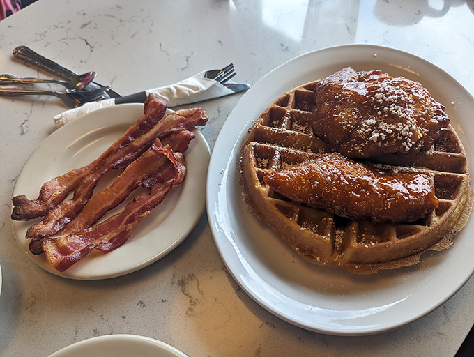Chicken and waffles with a side of bacon—breakfast and dinner eloping together on a plate, with maple syrup officiating the ceremony.