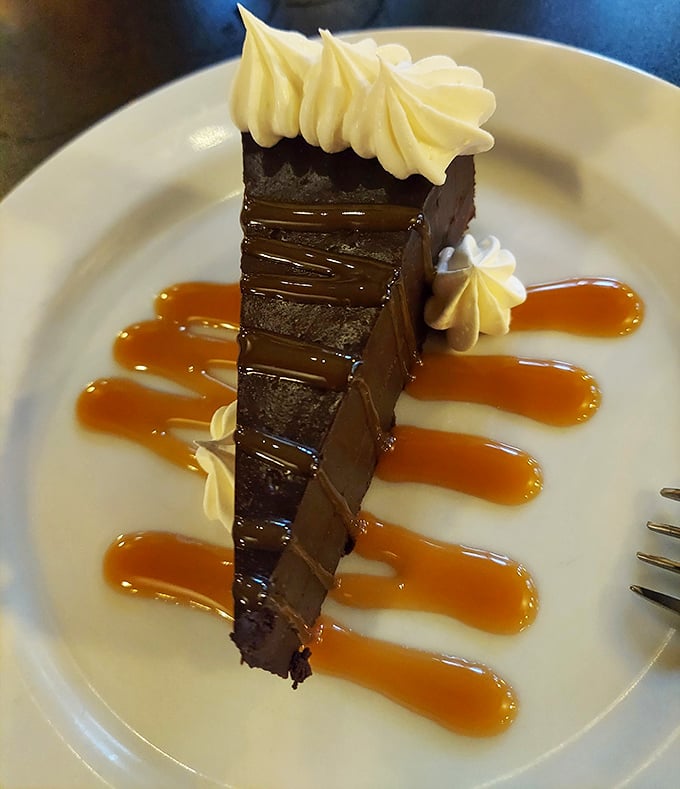 This chocolate cake slice isn't just dessert—it's an architectural masterpiece of layers drizzled with caramel ribbons.