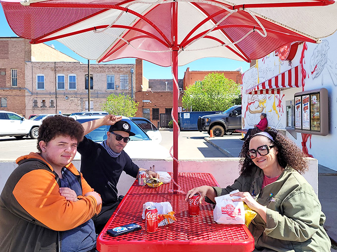 Outdoor dining at its most honest—red tables, cold drinks, and conversations punctuated by the occasional "mmm" of burger appreciation.