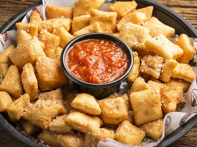 Dough nuggets dusted with Parmesan await their marinara bath—the appetizer that's secretly everyone's favorite part of the meal.
