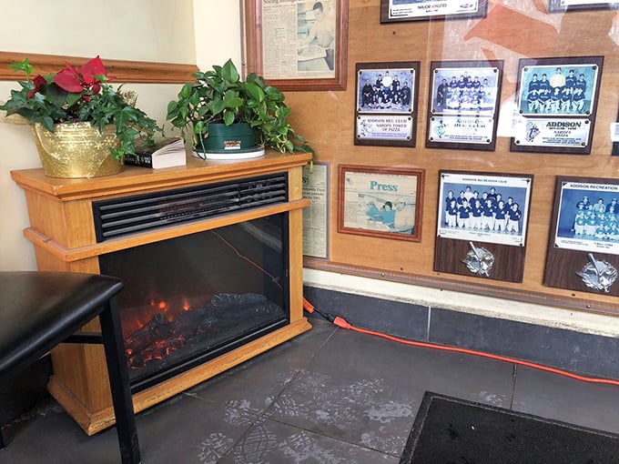 The electric fireplace and sports memorabilia wall—where community pride and cozy dining atmosphere come together.