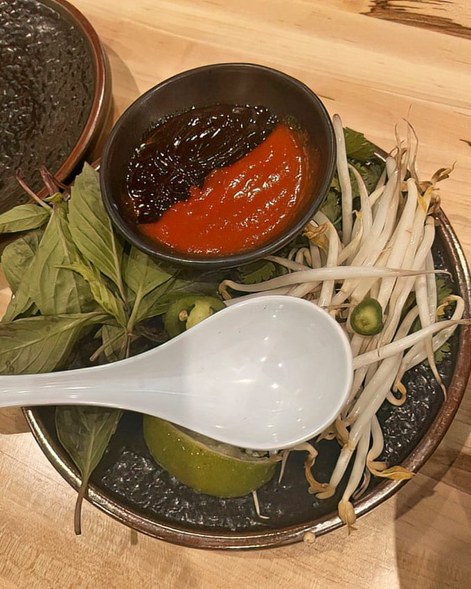 The pho accompaniments arrive like supporting actors ready for their big scene—fresh herbs, bean sprouts, and sauces waiting for their cue.