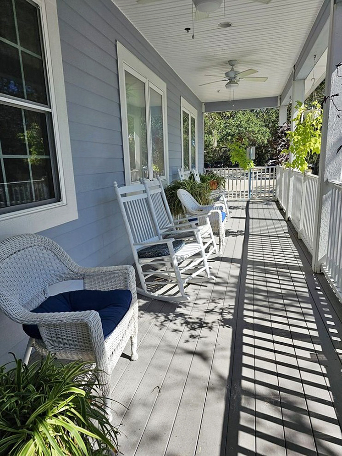The front porch that whispers "slow down." White rocking chairs, dappled sunlight, and the gentle invitation to breathe in that coastal air.