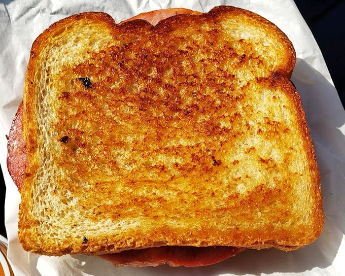 The perfectly golden grilled cheese—butter-kissed bread embracing melted American cheese—proves that three simple ingredients can create something greater than their sum.