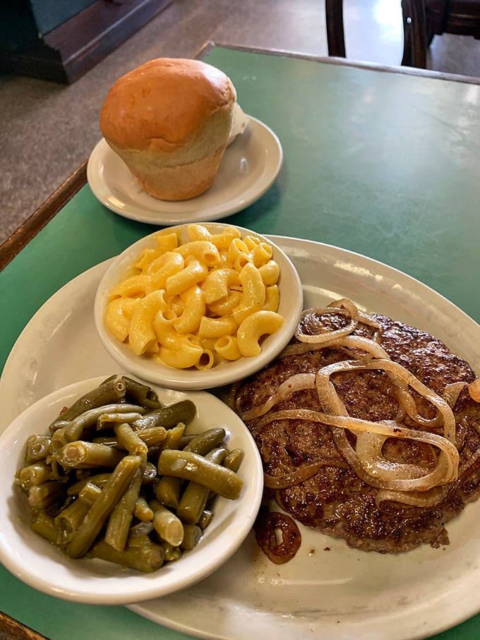 The hamburger steak with grilled onions, green beans, and mac and cheese—a plate that says "You won't need dinner tonight." That roll is just showing off.