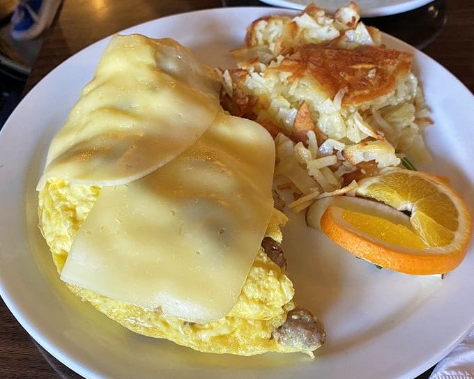 Cheese melting over an omelet like a warm blanket on a cool morning. The hash browns stand guard, crispy soldiers protecting your breakfast joy.