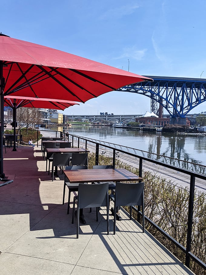 Riverside dining that makes you wonder why you ever eat indoors. Those red umbrellas aren't just shade—they're exclamation points on a perfect afternoon.