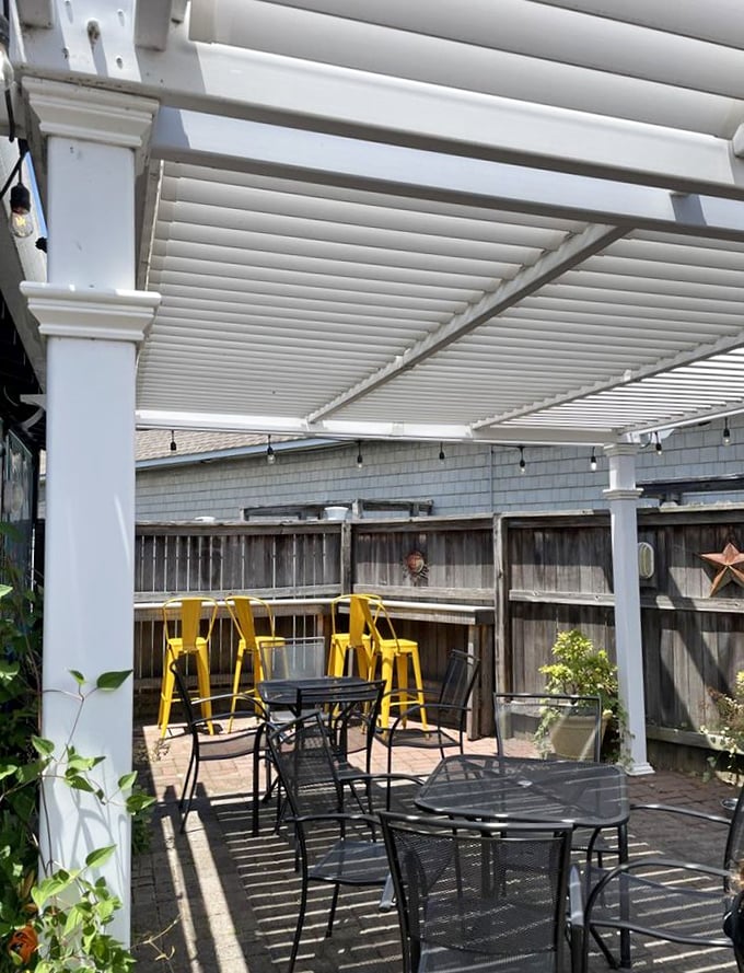 The outdoor patio—where vitamin D meets vitamin Sea. Those yellow bar stools practically shout "stay awhile" against the crisp white pergola.