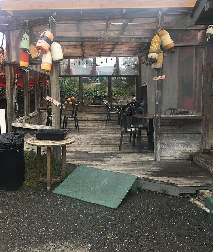 The weathered patio, adorned with colorful buoys, offers a dining experience where the Pacific provides both the menu and the atmosphere.