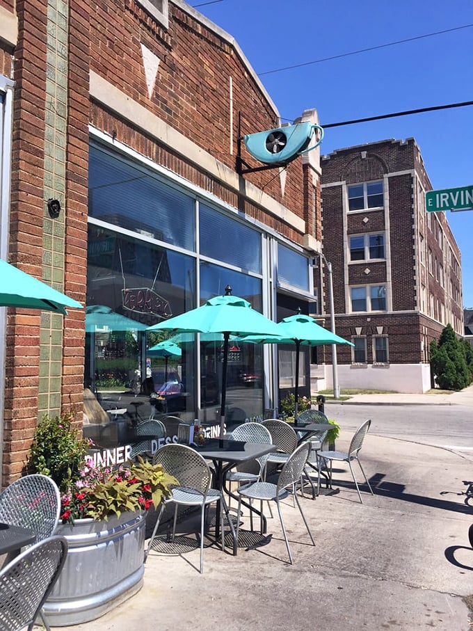 Sidewalk seating under turquoise umbrellas offers a front-row seat to East Side life. Urban dining with a side of people-watching.