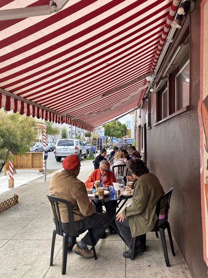 Sidewalk dining under a classic red and white striped awning—where Mission District conversations blend with the clinking of coffee cups and forks.