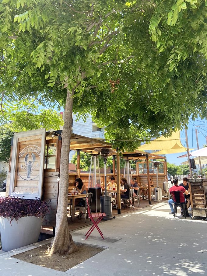 Outdoor seating under leafy shade – nature's dining room for enjoying ocean treasures in urban LA.