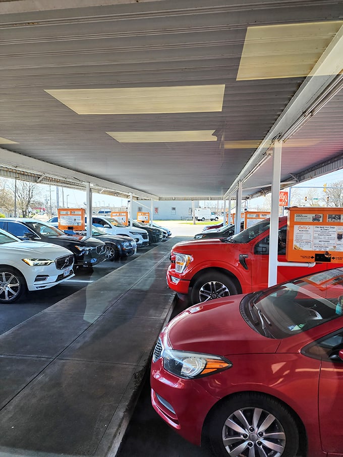 The covered parking area – where cars gather like hungry pilgrims at a shrine to American comfort food. Every space tells a story.