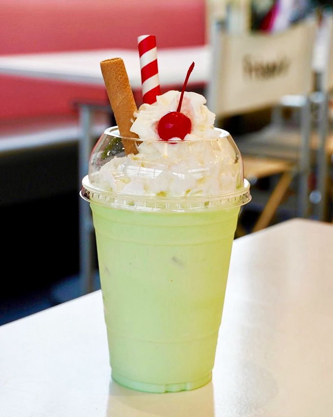 The pistachio almond milkshake – a pale green dream topped with whipped cream, a cherry, and a cookie. Dessert masquerading as a beverage.