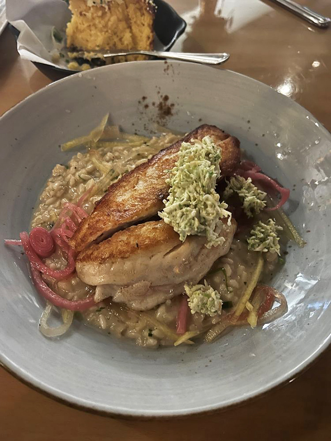 A perfectly seared fish fillet rests atop a bed of savory goodness. Those pickled red onions add just the right punch of color and tang.