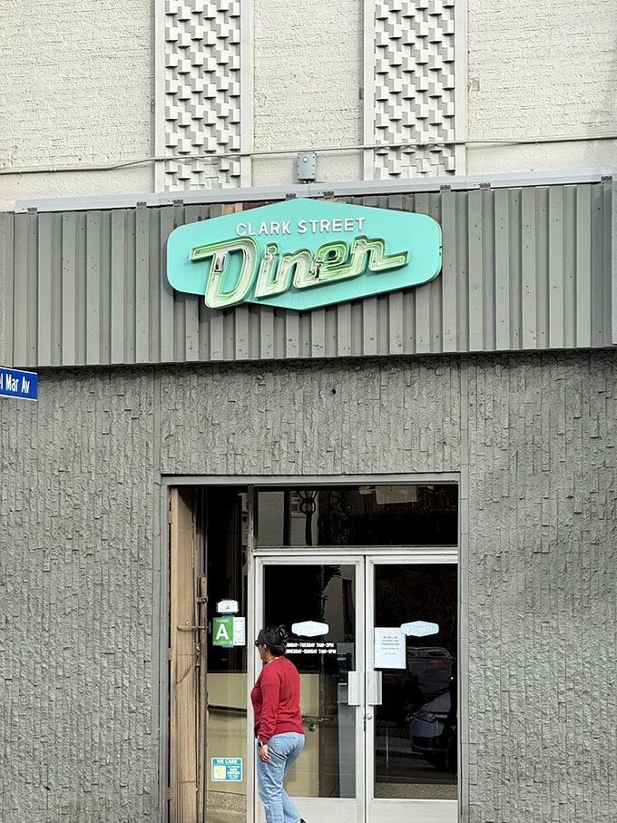 The iconic mint-green sign against textured concrete—architectural details that say "this isn't just another diner" before you even taste the food.