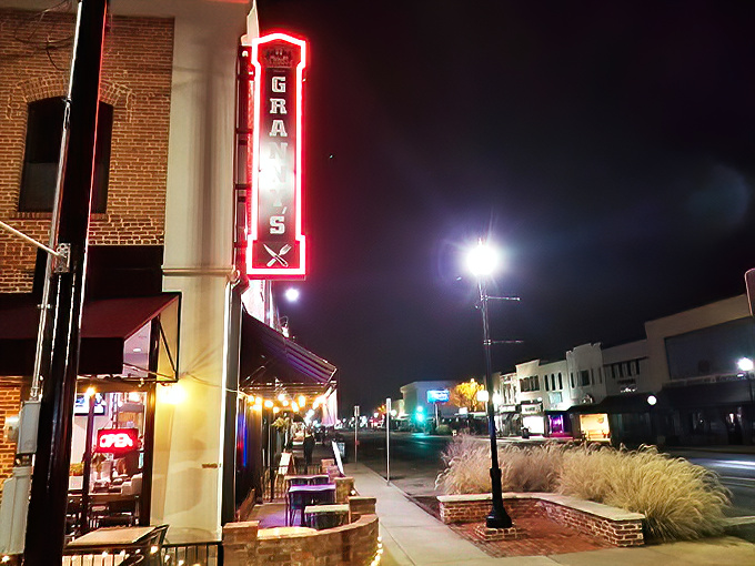 The vertical neon sign glows like a lighthouse for late-night comfort food seekers navigating downtown Stillwater after dark.