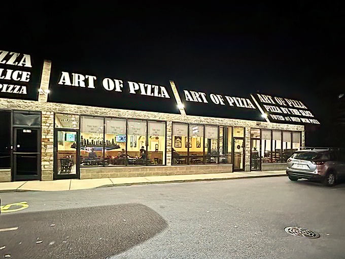 By night, Art of Pizza's warm glow beckons hungry travelers like a lighthouse guiding ships to safe, delicious harbor.
