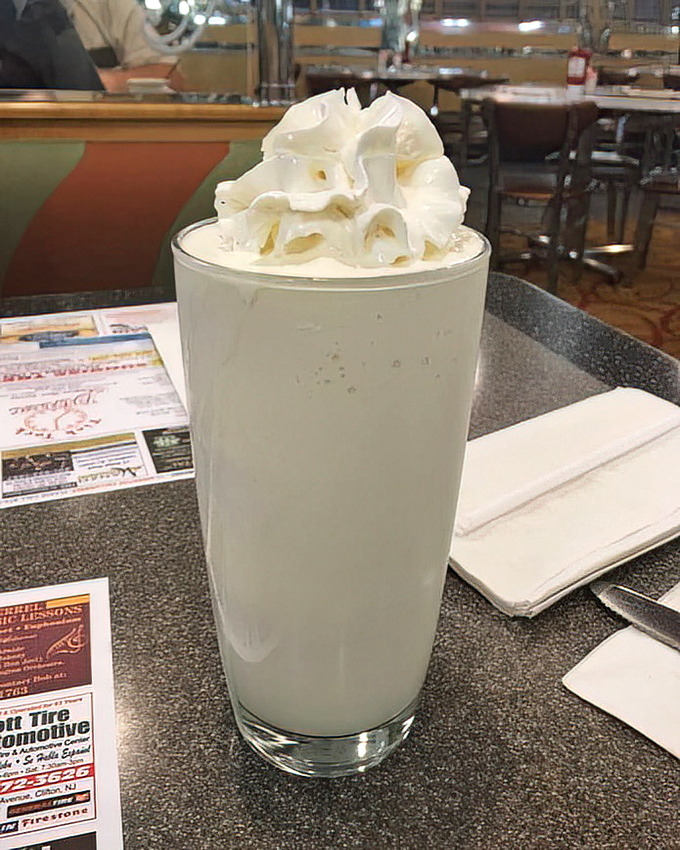 This vanilla shake isn't just a drink—it's a tower of creamy nostalgia topped with a cloud of whipped cream that defies both gravity and restraint.