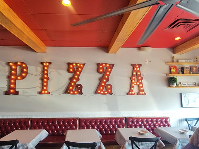 Those illuminated PIZZA letters aren't just decor—they're a promise. The red banquette seating below stands ready for those serious about their Italian feast.