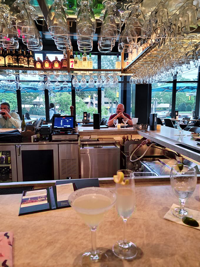 The bar at Perry's doesn't just serve drinks—it showcases liquid architecture. Glasses hanging like crystal stalactites above premium spirits.