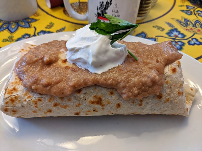 A breakfast burrito so perfectly wrapped it could teach a class on organization, topped with a dollop of sour cream that's practically a cloud.