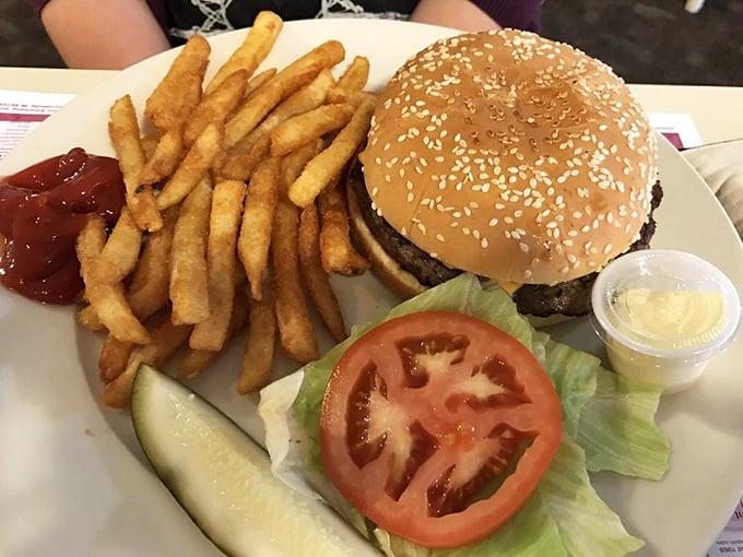 The classic American burger in its natural habitat—accompanied by crisp fries, a pickle spear, and the promise of satisfaction.