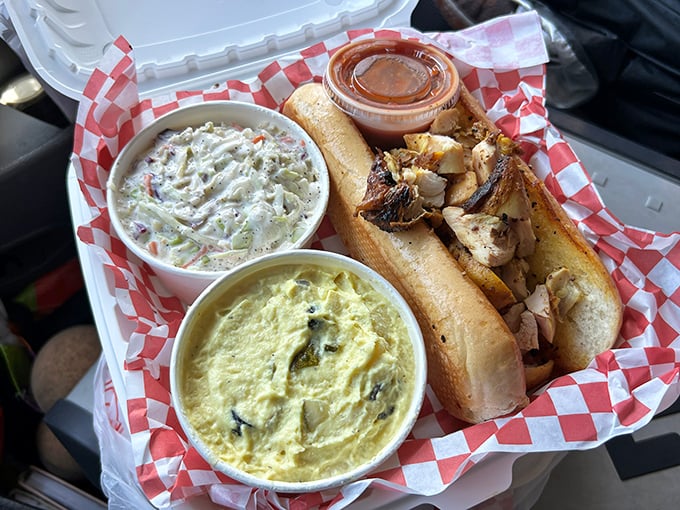 A proper chicken sandwich flanked by coleslaw and potato salad—the holy trinity of BBQ sides that turns a simple lunch into a celebration.