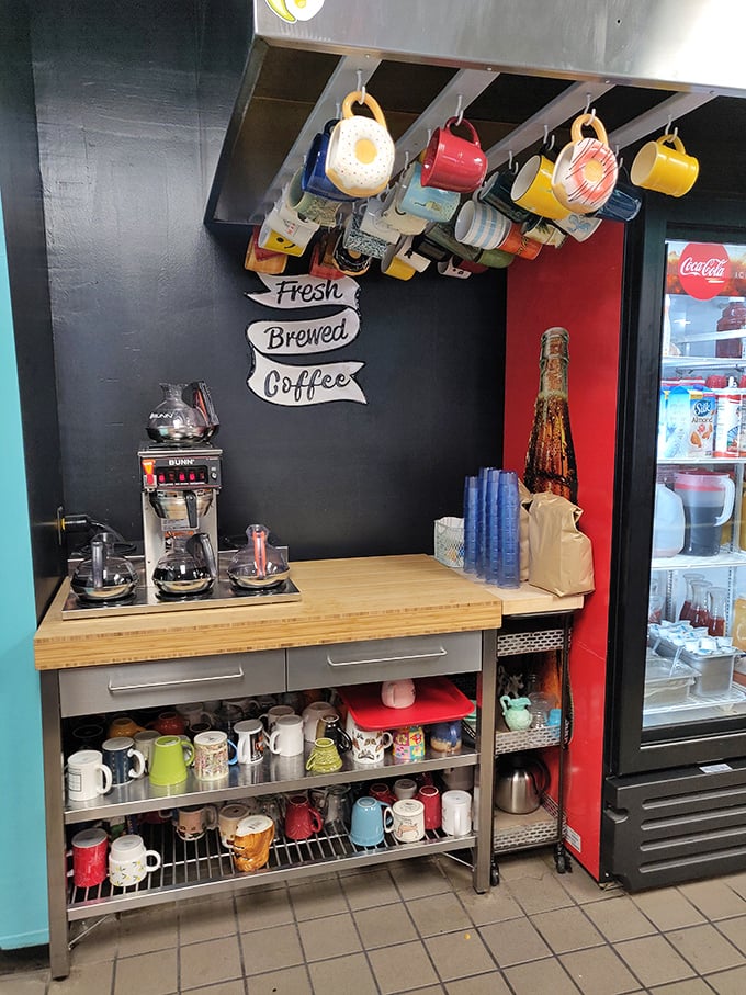 The coffee station—sacred ground where morning magic begins, with mugs hanging like trophies commemorating victories over early wake-up calls. 