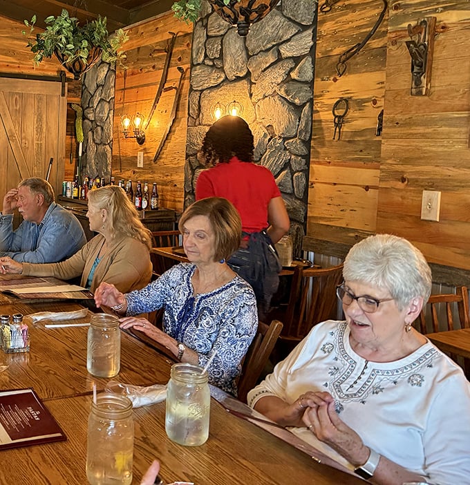 Diners enjoying the warm wooden interior with stone accents—where conversations flow as freely as the sweet tea refills.