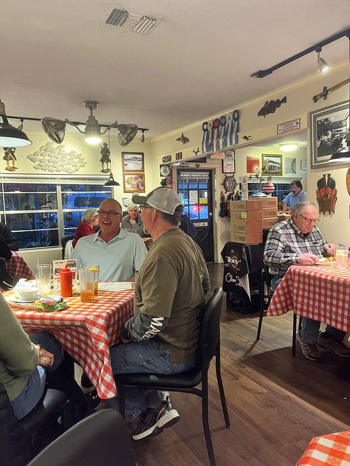 Happy diners sharing stories and seafood—the universal language of a great meal bringing strangers together under a ceiling festooned with fishing memorabilia.