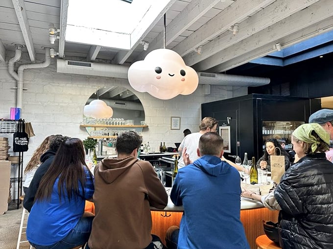 Happy diners gathered at the bar under that smiling cloud lamp—a community united by the universal language of exceptional pizza.