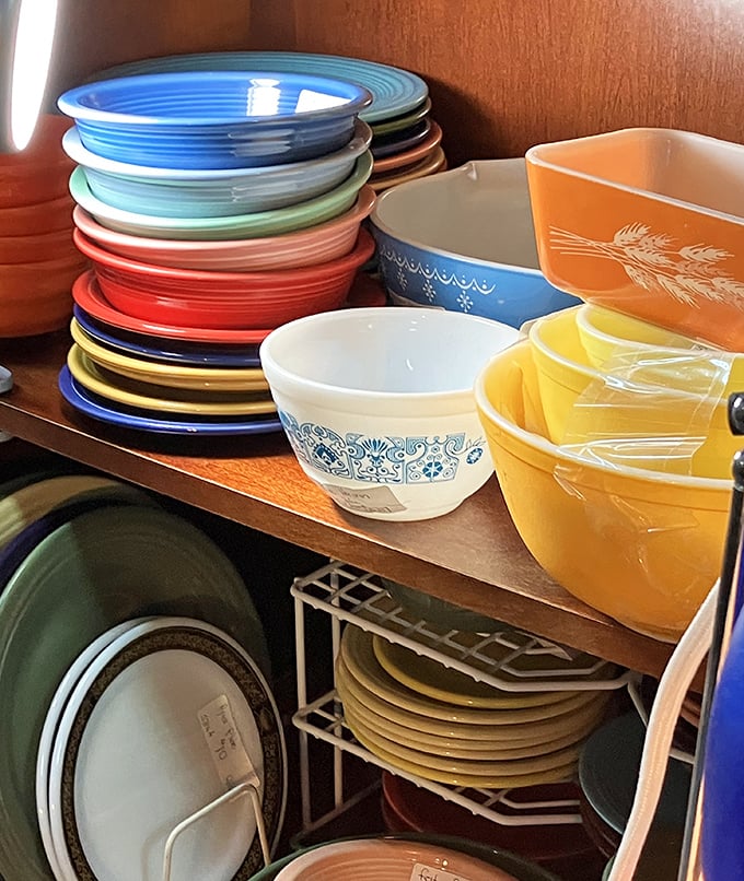 Fiestaware heaven for collectors—those stacked rainbow plates could brighten any dinner party. The blue cornflower pattern below screams "vintage Corningware."
