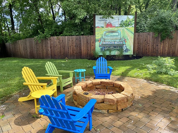 Colorful Adirondack chairs surround a stone fire pit, creating an outdoor gathering space that begs for twilight conversations.