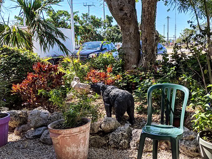 Garden seating surrounded by tropical plants and a black bear statue – because Florida never got the memo about conventional restaurant décor.