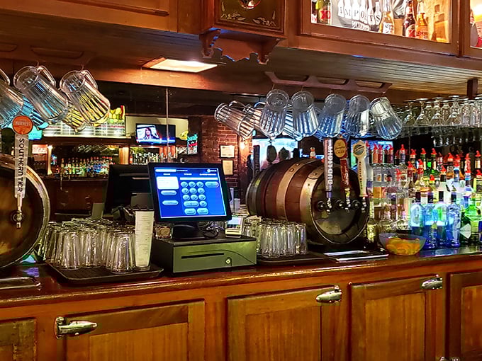 Behind the bar, where magic happens – glasses hanging like crystal stalactites above a wooden landscape of bottles and taps.