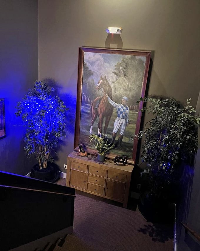 Descending these stairs feels like entering a racing museum after hours. The oversized jockey painting watches over guests like a friendly guardian of good taste.
