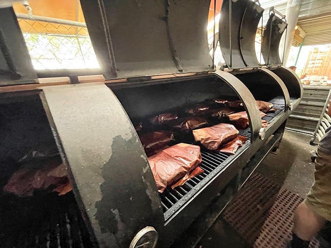 The smokers – where patience transforms tough cuts into tender treasures. These metal beasts work their low-and-slow alchemy day and night.